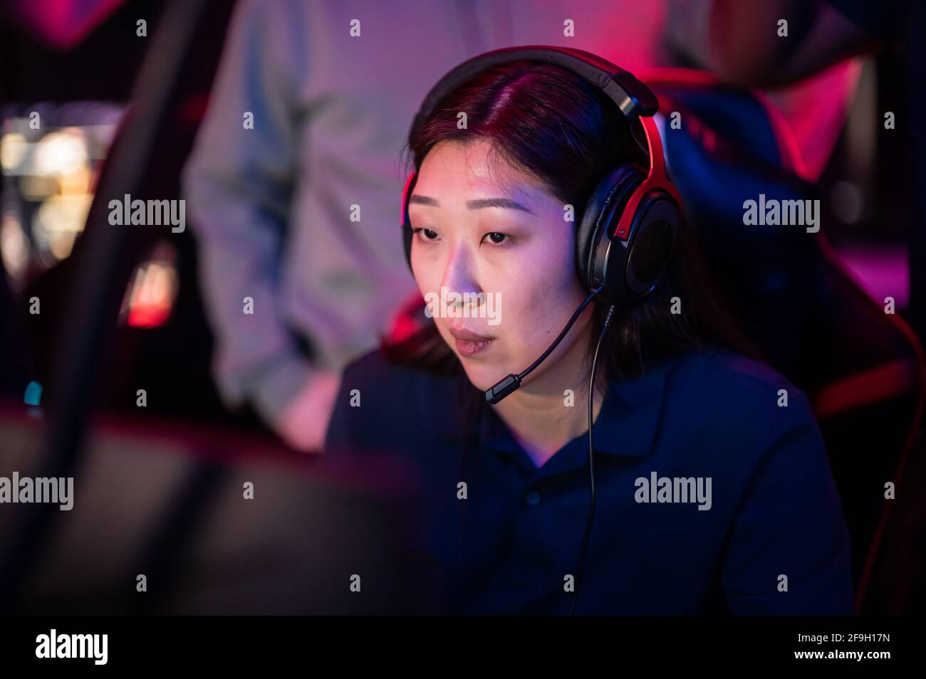 A close-up portrait of a gamer girl wearing headphones in a computer ...