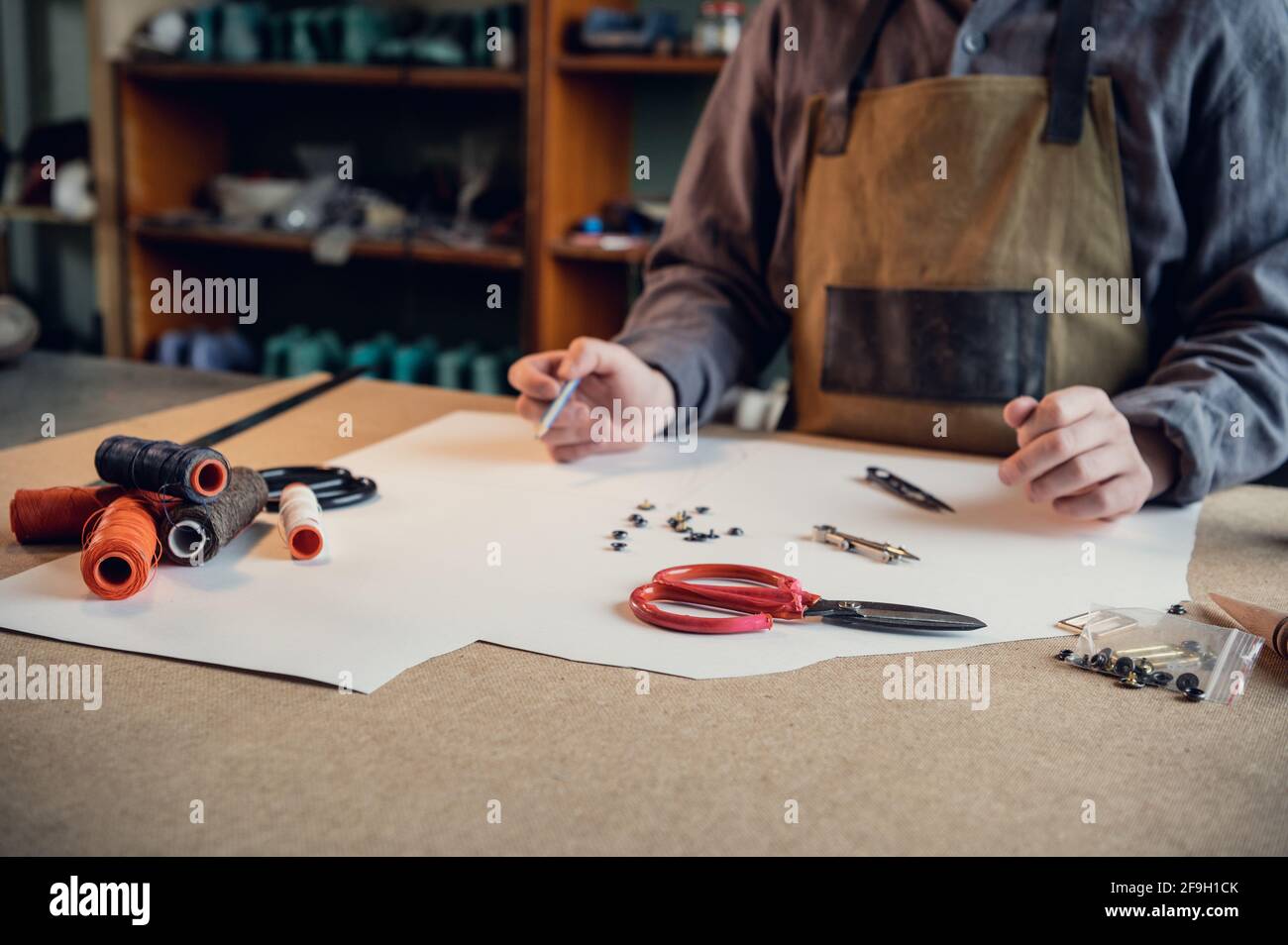 An experienced shoemaker in a shoe production workshop makes a pattern ...