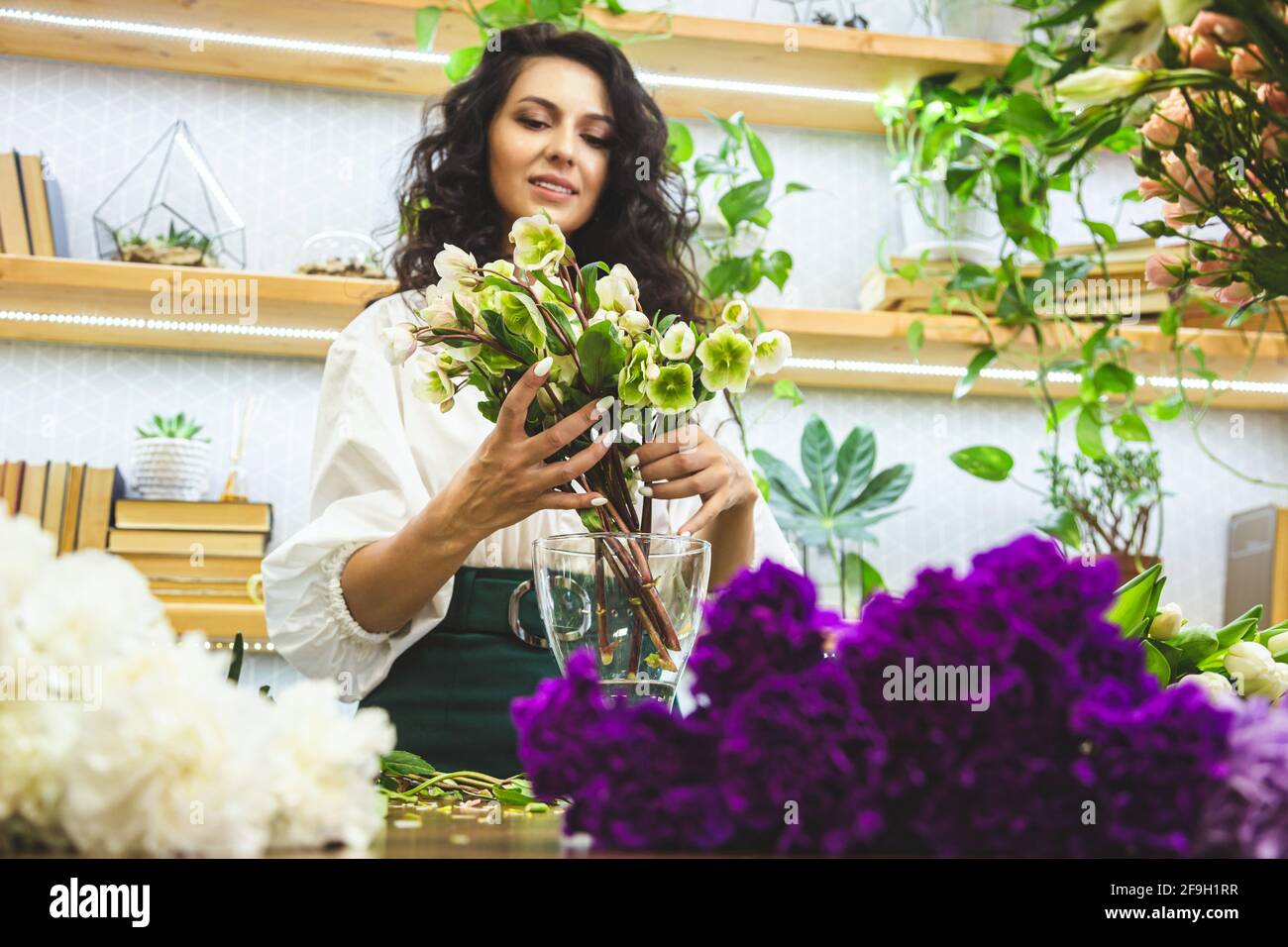 Attractive young woman florist is working in a flower shop Stock Photo ...