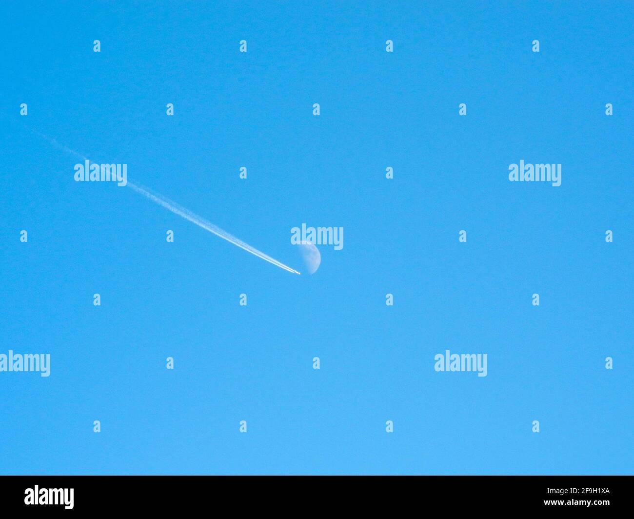 An airplane sky track near the moon in the blue sky Stock Photo - Alamy