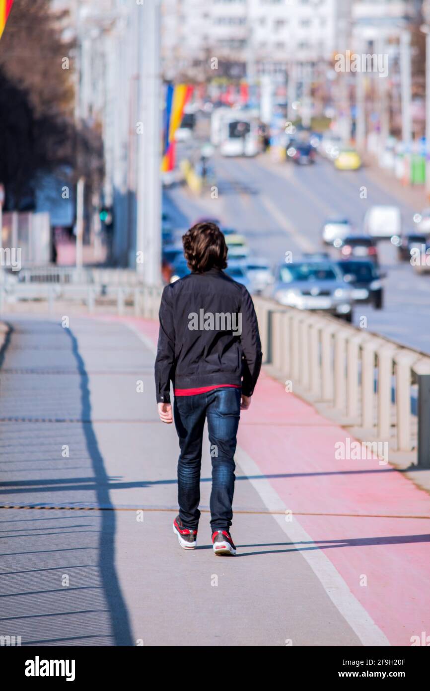 A vertical shot of a person walking on a bridge on blurred background ...