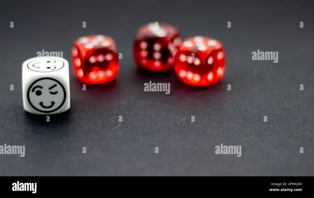 white dice with emoticon markers and red dice in the background blurred ...