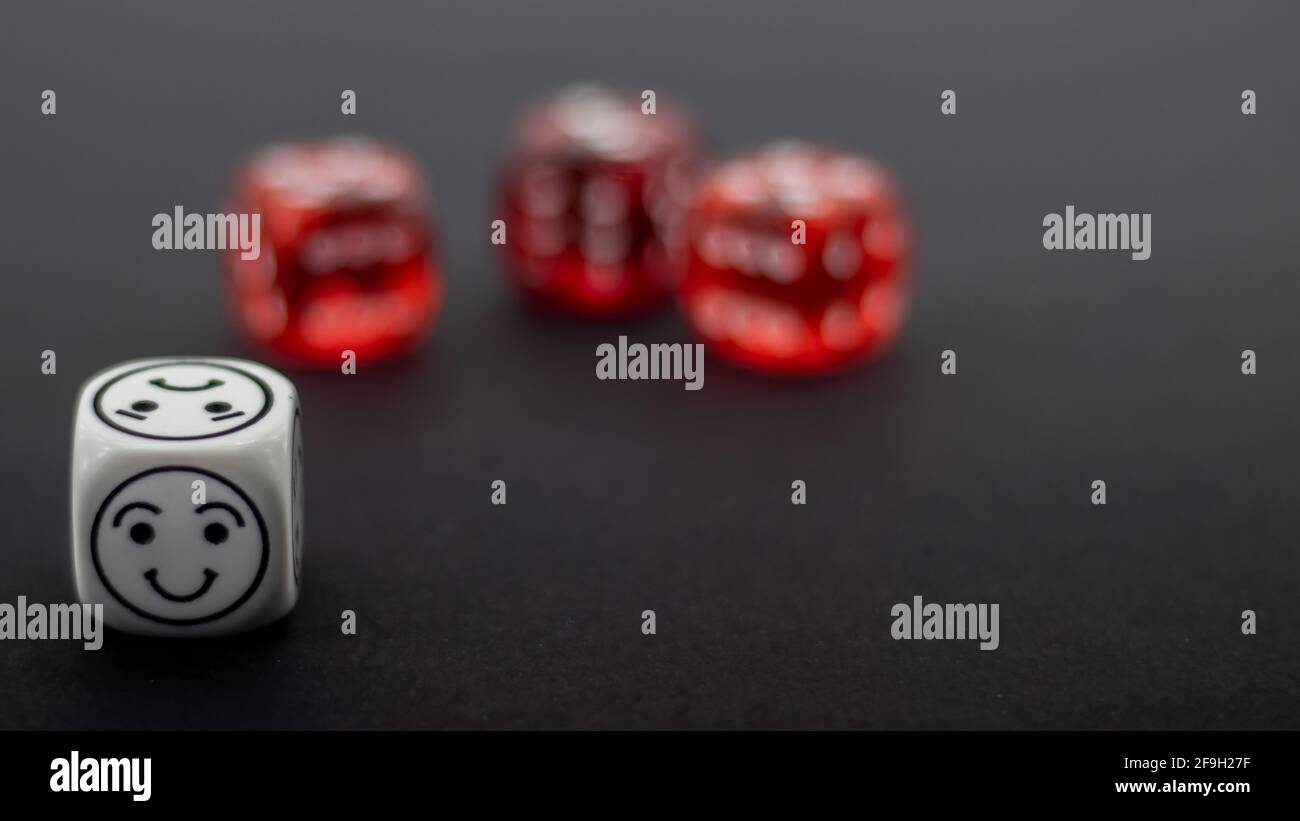 white dice with emoticon markers and red dice in the background blurred ...