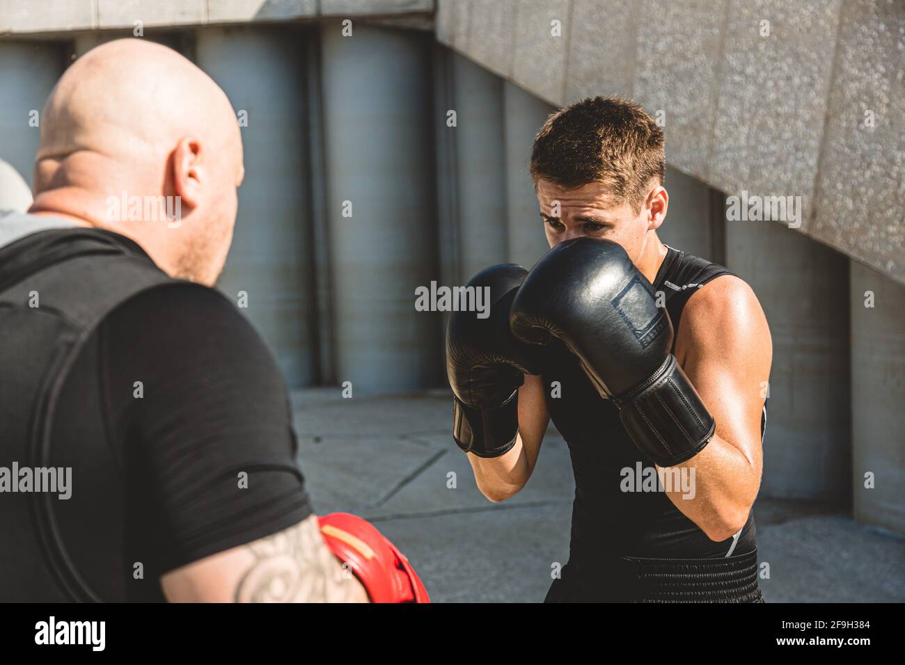 Two men exercising and fighting in outside. Boxer in gloves is training ...