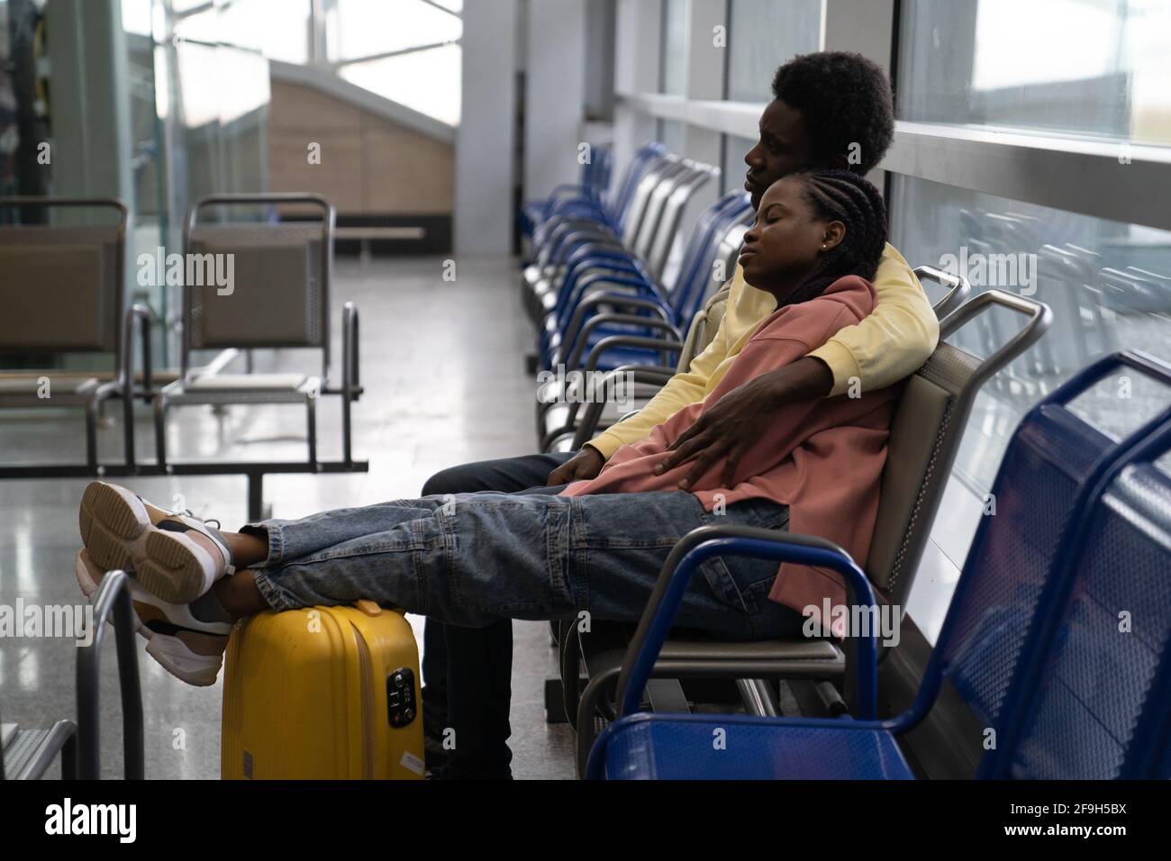 African couple sleep on chairs in waiting room of airport, tired wait ...