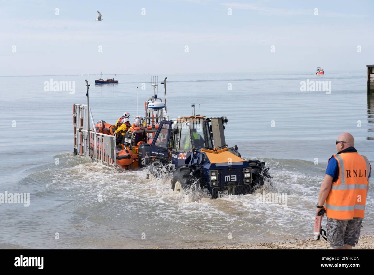 RNLI volunteer watches the beach tractor and lifeboat launching into ...