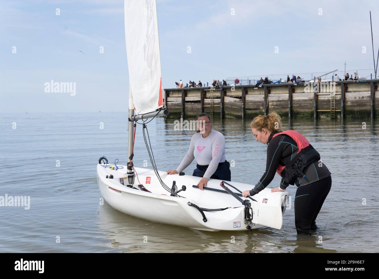 Two women are getting boat ready for sail in the sea near Whitstable ...