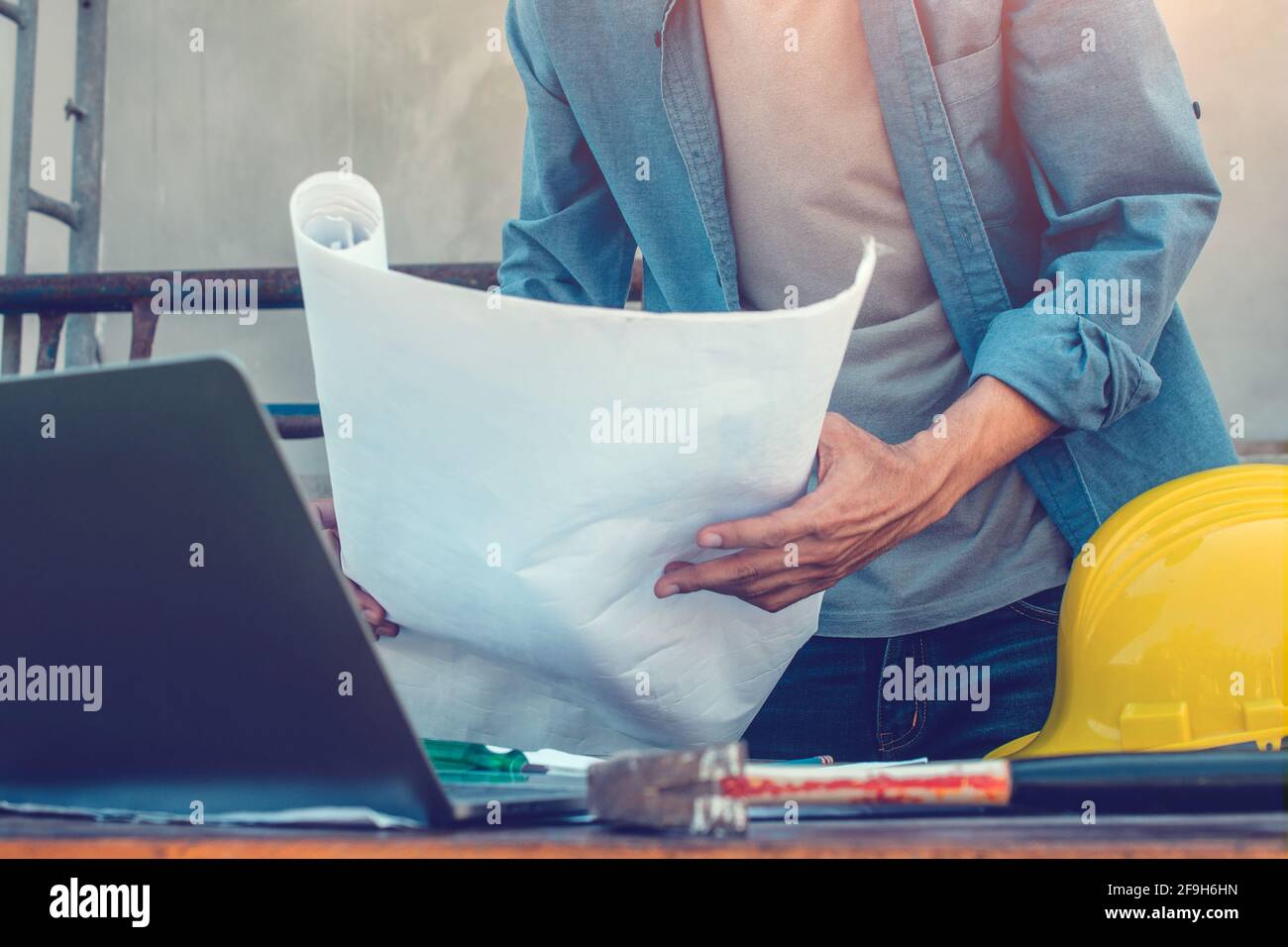 Engineer holding blueprint working on site construction Stock Photo - Alamy