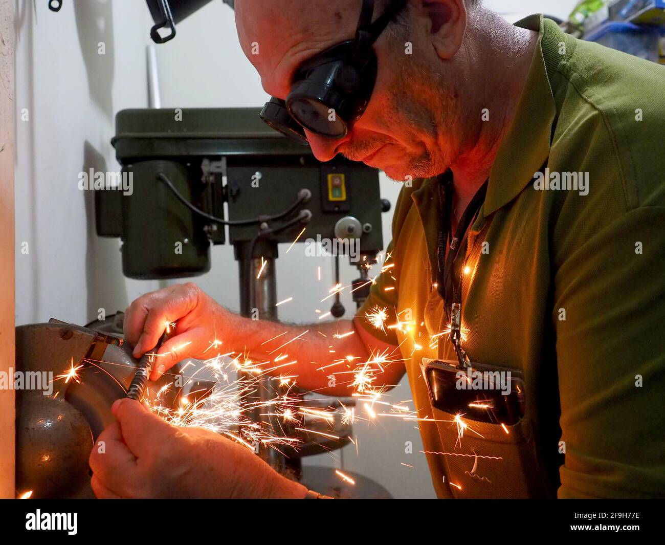 Man operating a bench grinder in a bicycle workshop. In Peru, since the ...