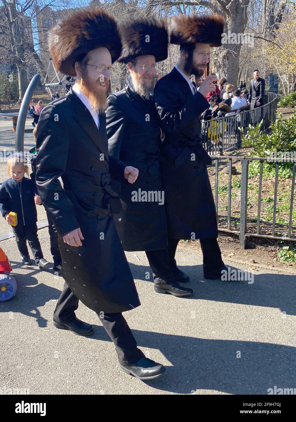 Three orthodox Jewish Hasidic friends and fathers walk together in ...