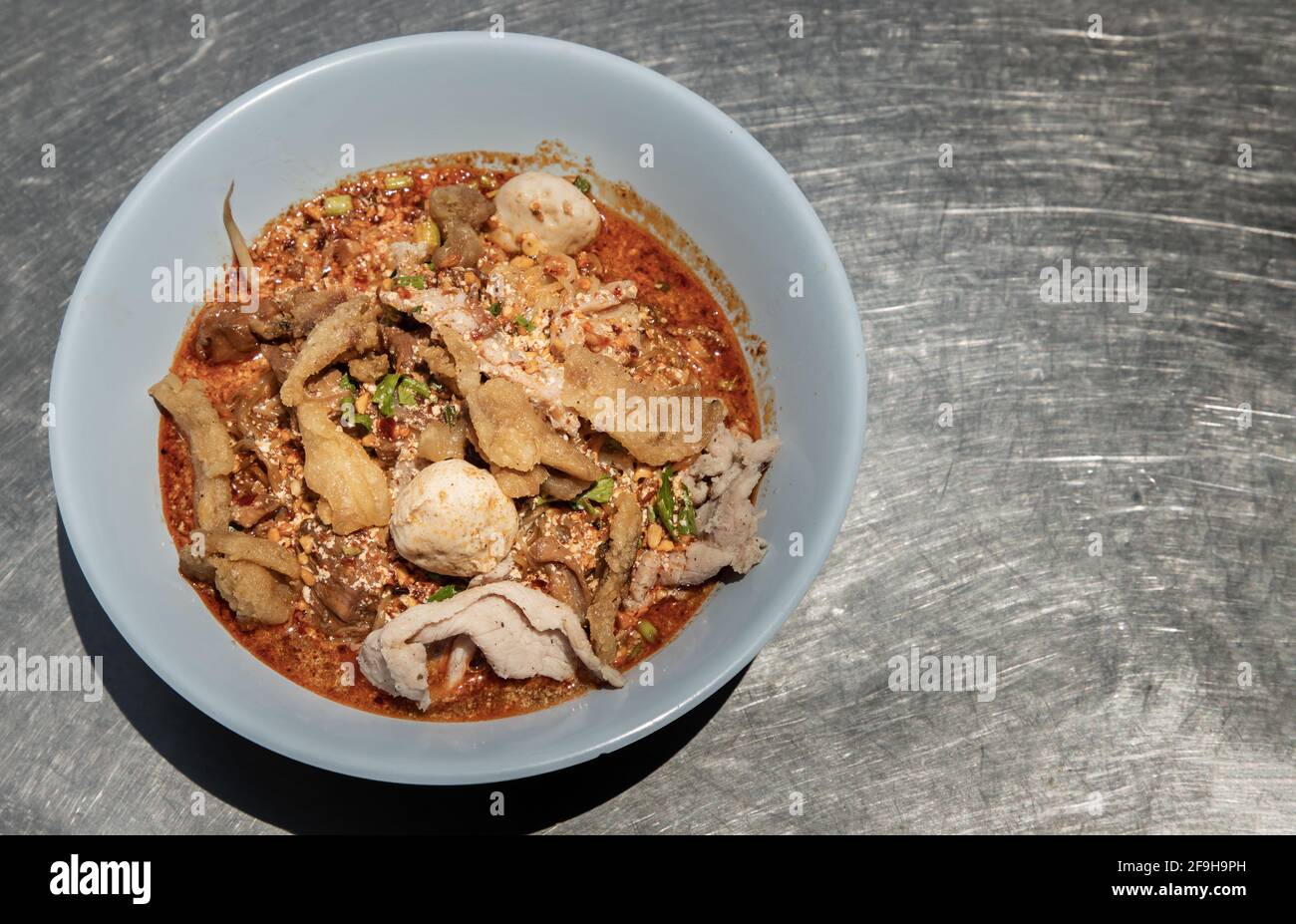 Egg noodles in Thai spicy soup with braised pork, pork balls and fatty ...