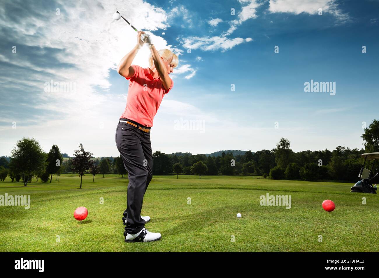 Young female golf player on course doing golf swing, she presumably ...