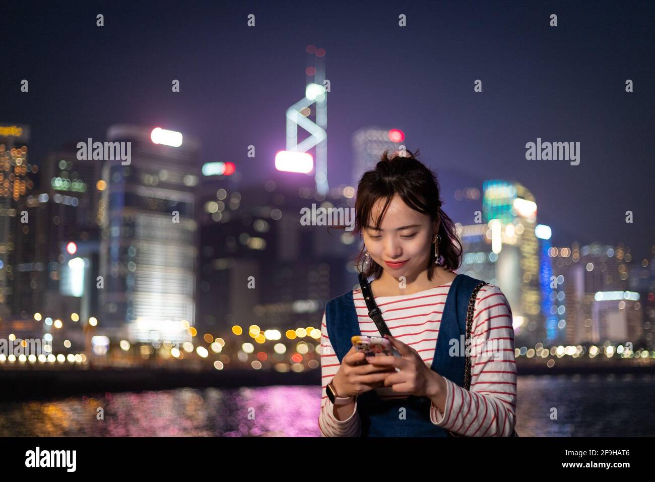 asian young lady with face mask messages and reads on mobile phone with ...