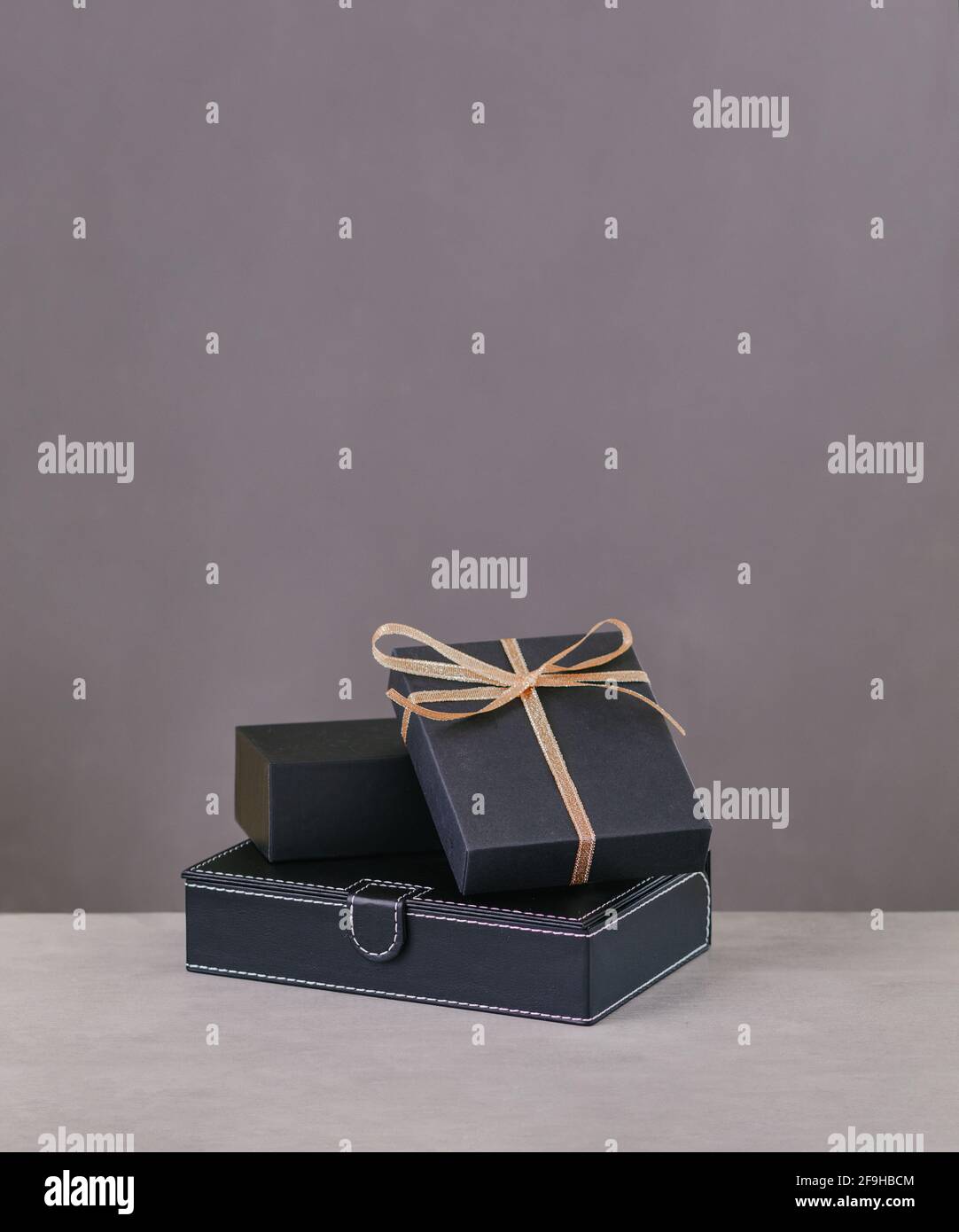 Back gift box. Golden ribbon on gift on a grey background. Copy space ...