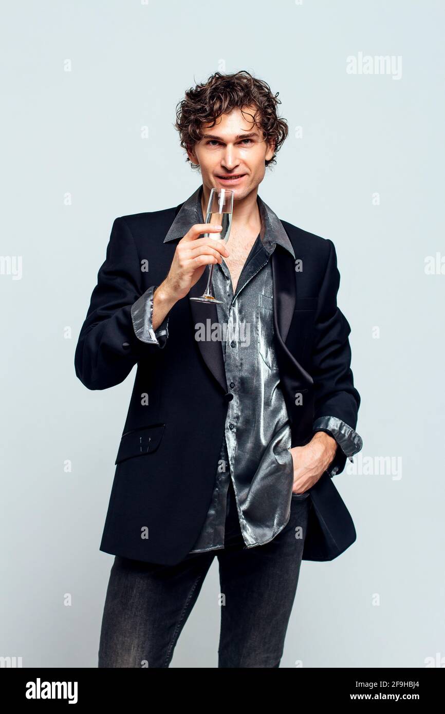 Tall handsome confident young man in a jacket holding glass of wine ...