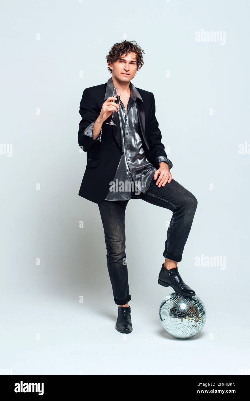 Tall handsome confident young man in a jacket holding glass of wine ...