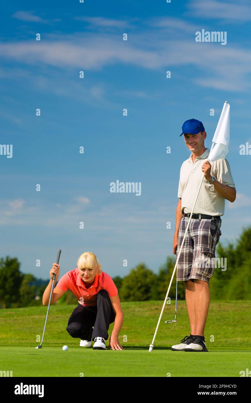 Young female golf player on course putting, she aiming for her put shot ...
