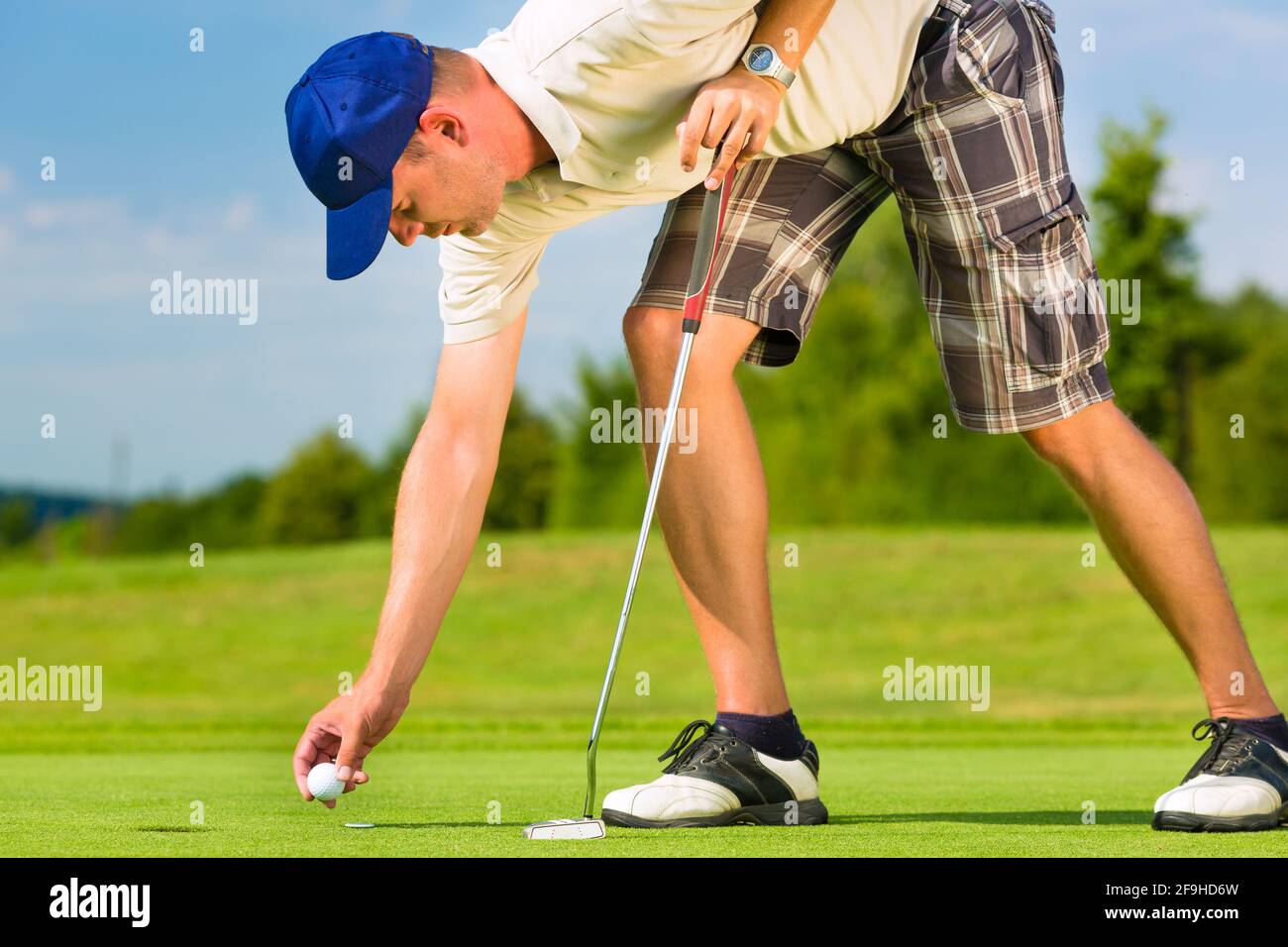 Young golf player on course putting, he is putting at the green Stock ...