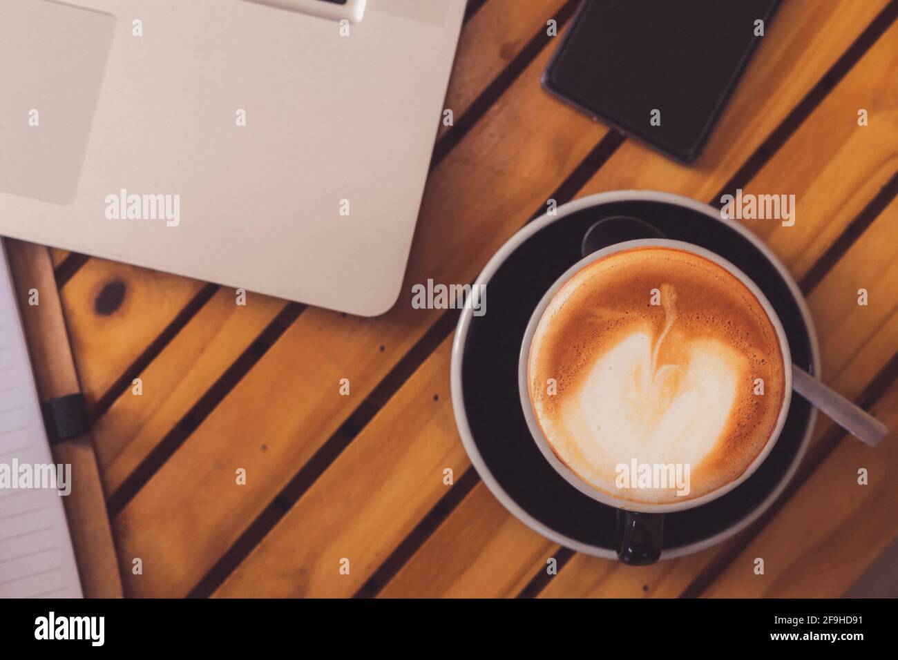 Top view hot coffee cup with blur laptop smarthphone and note book on ...