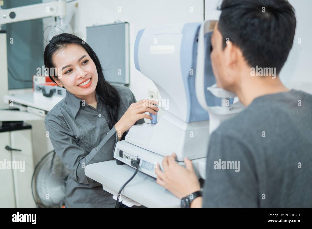 a female doctor and a male patient doing an eye check using a device ...