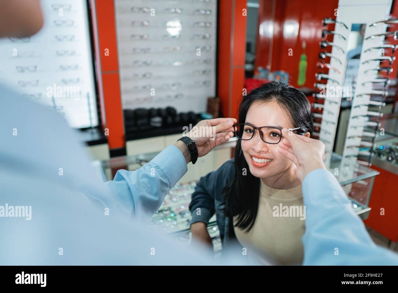 an employee's hand is helping to put on a pair of glasses that a woman ...