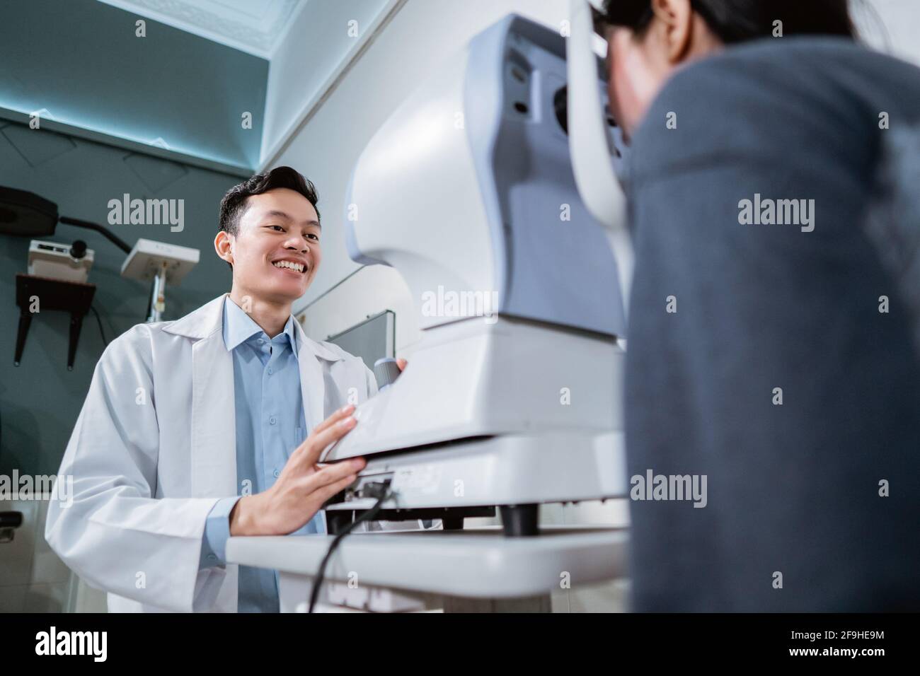 a male doctor and a female patient doing an eye check using a device ...