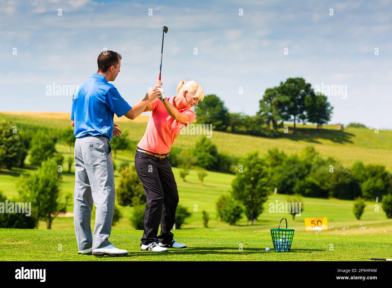Young female golf player at Driving Range with a Golf Pro, she ...