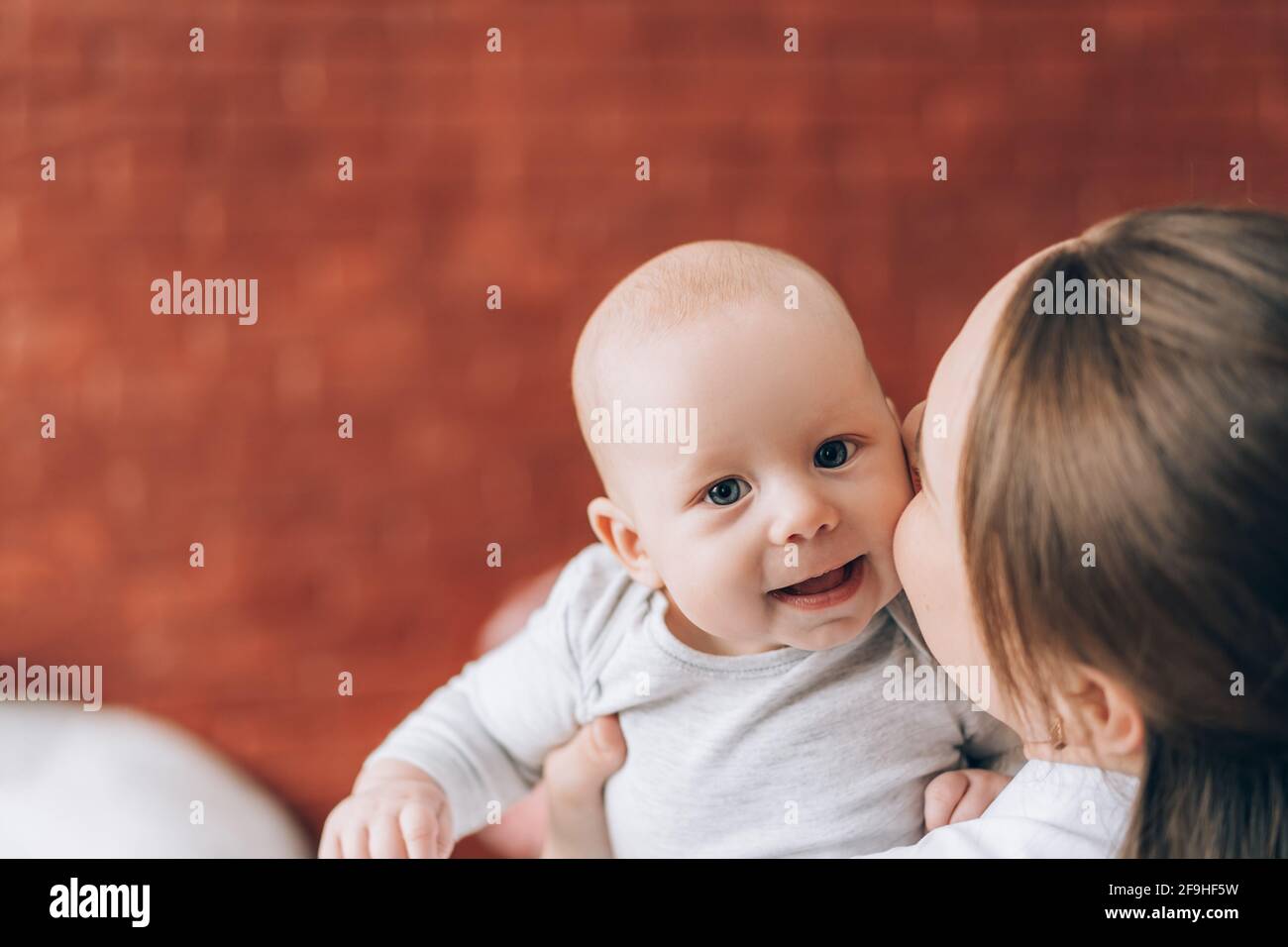 Young mother plays and kisses her newborn baby. Love and care for ...