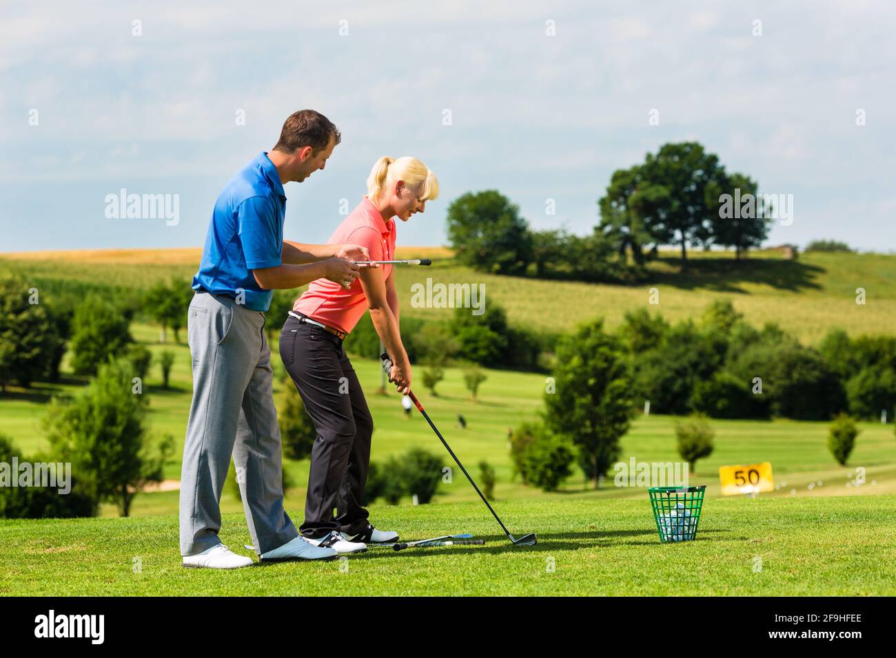 Young female golf player at Driving Range with a Golf Pro, she ...