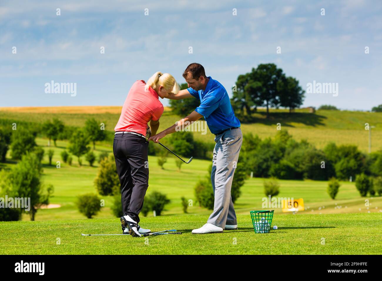 Young female golf player at Driving Range with a Golf Pro, she ...