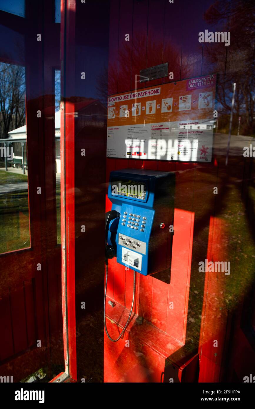 A red phone booth, inside there is a blue push-button phone with ...