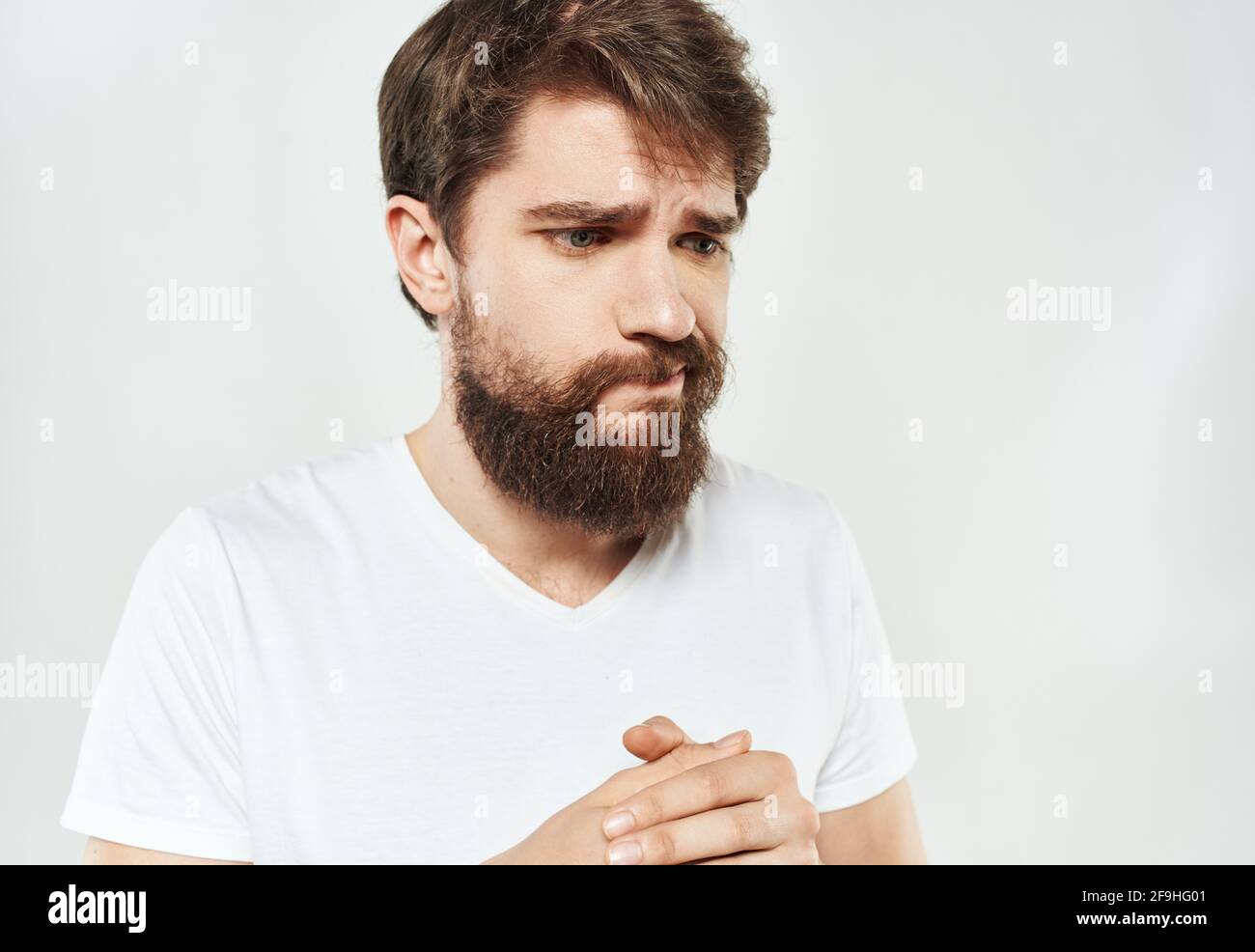 Bearded man in a white T-shirt on a light background sad face emotions ...