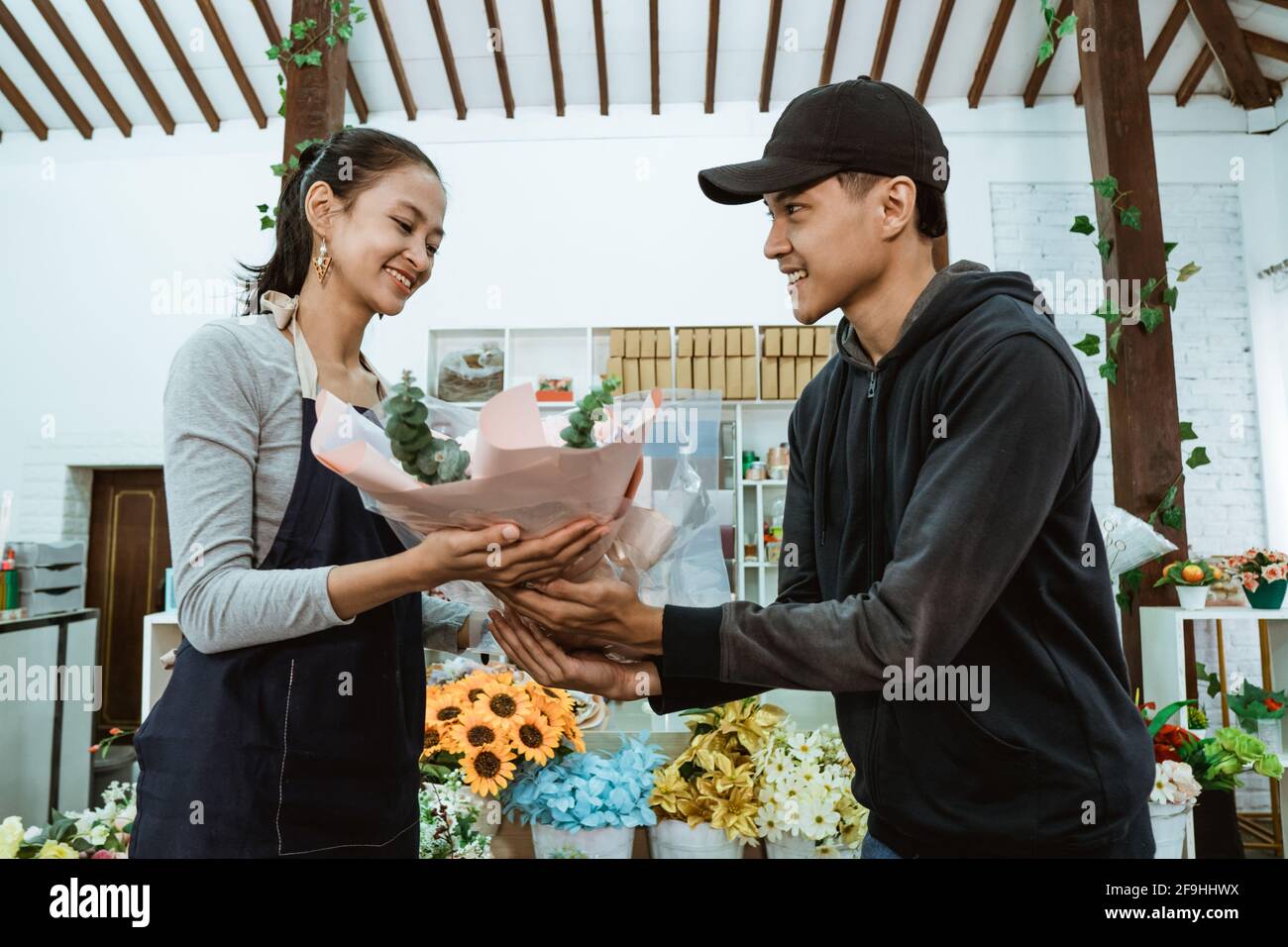 smiling young female shopkeeper wearing a apron. servicing male flannel ...