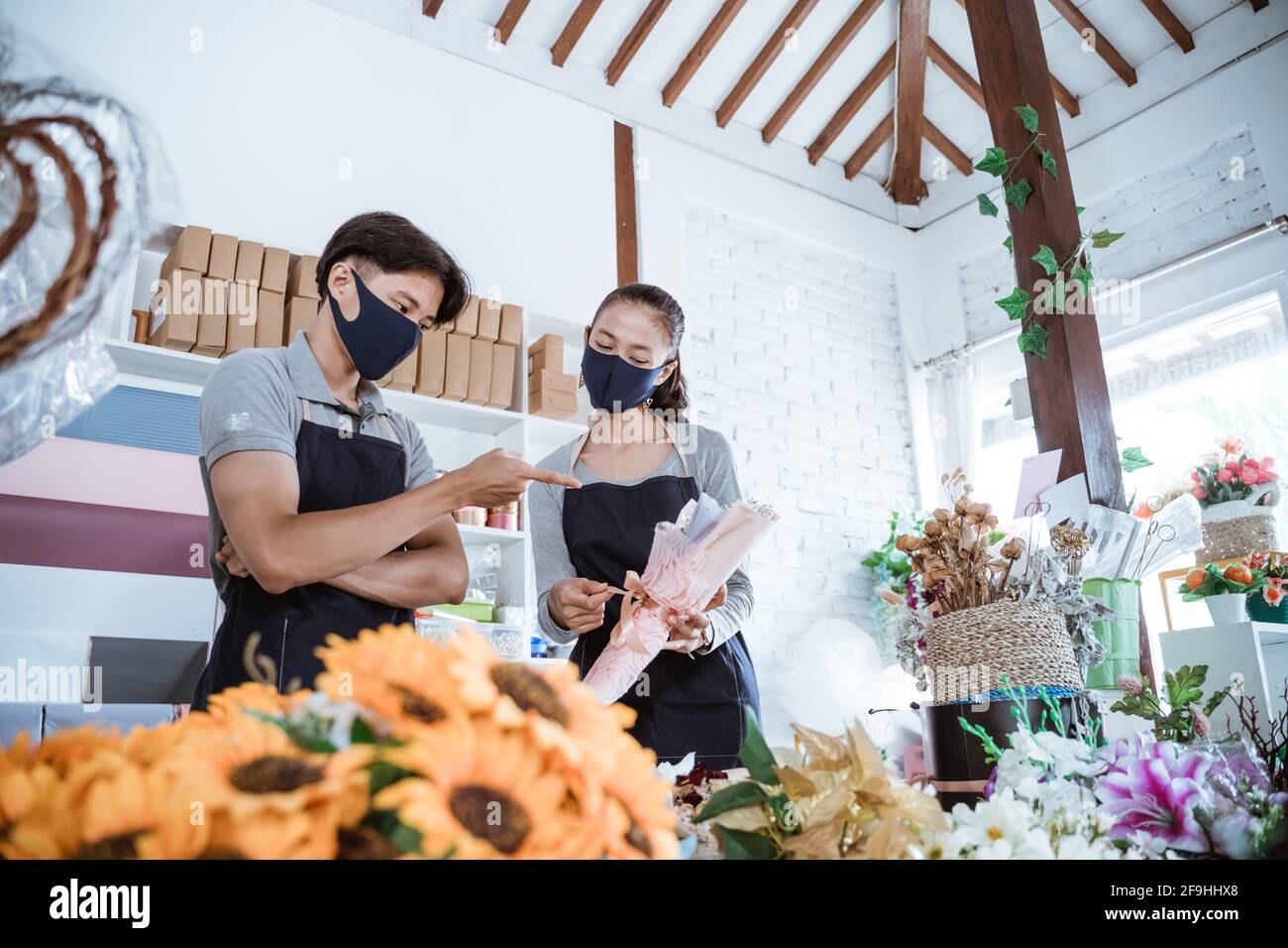 portrait young florist standing discussing Fresh flowers with friend in ...