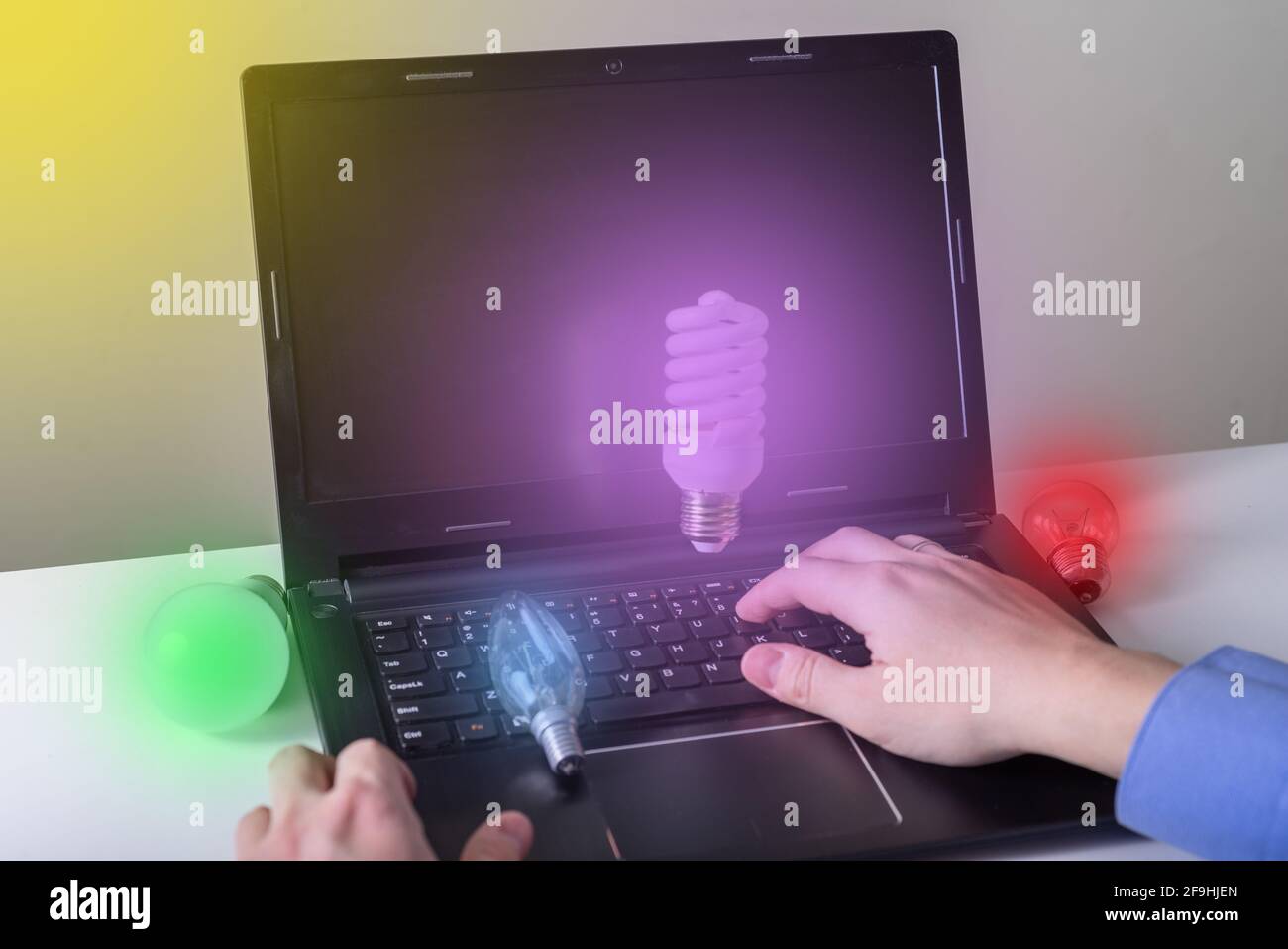 Light bulbs of different colors and a keyboard. Hands on the keyboard ...