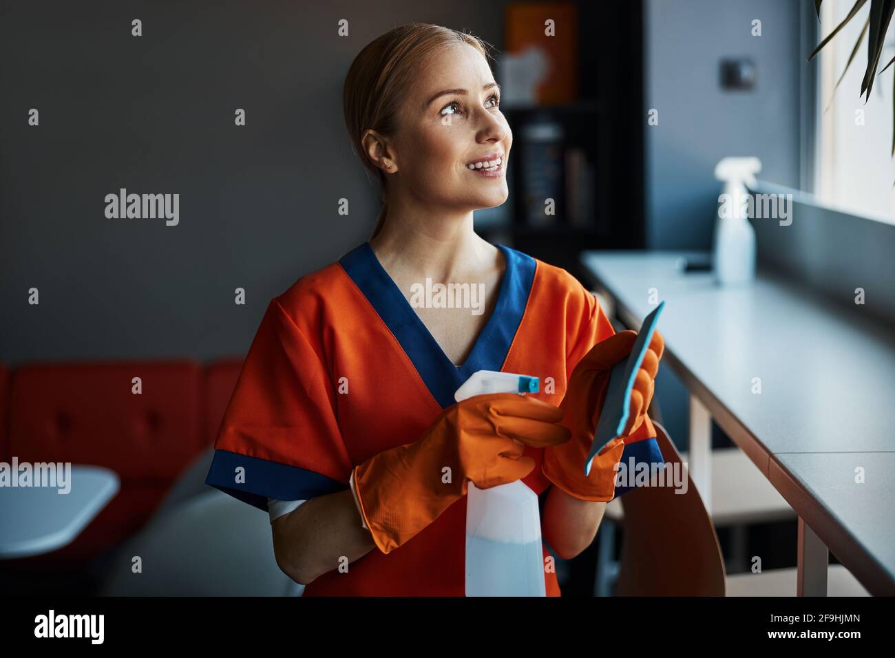 Smiling female worker in the rubber gloves holding cleaning tools Stock ...