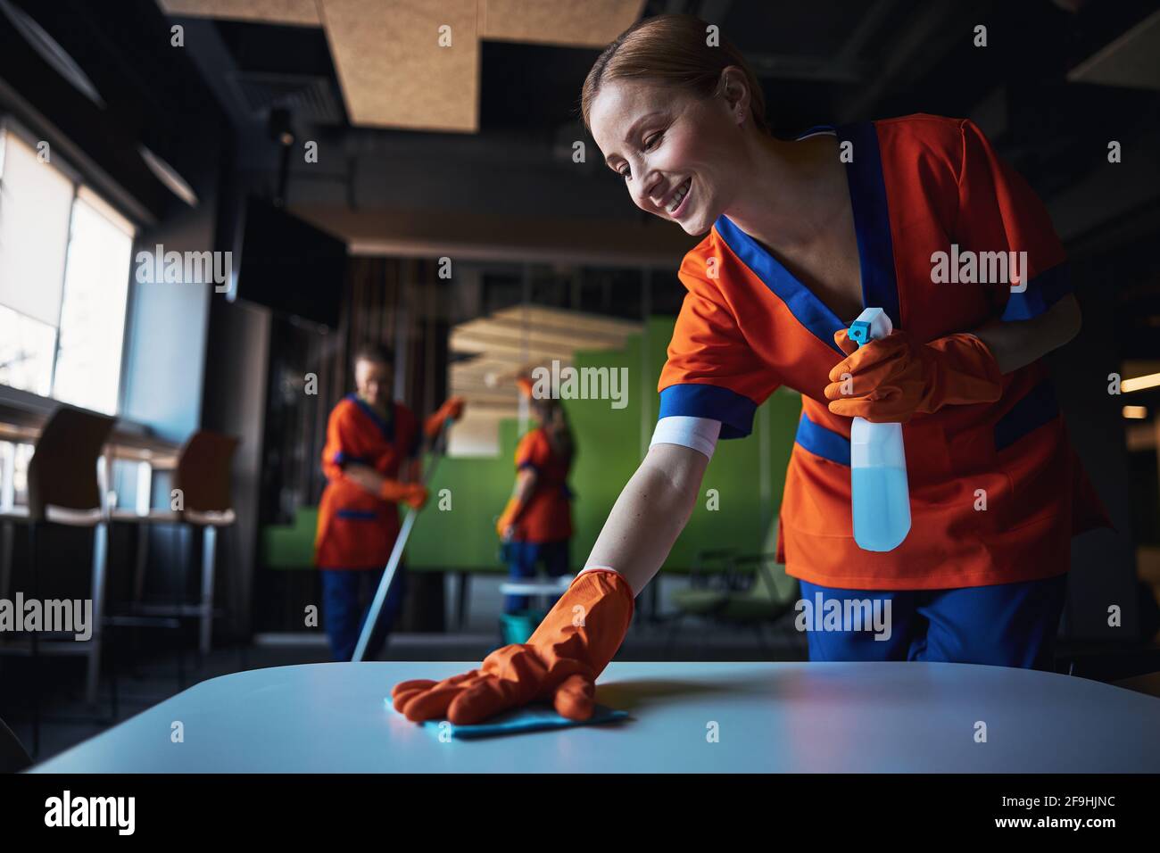 Three female workers using various janitorial supplies during the clean ...