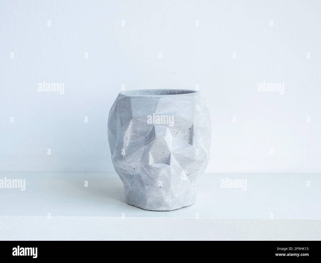 Empty skull shape concrete plant pot on white wooden shelf isolated on ...