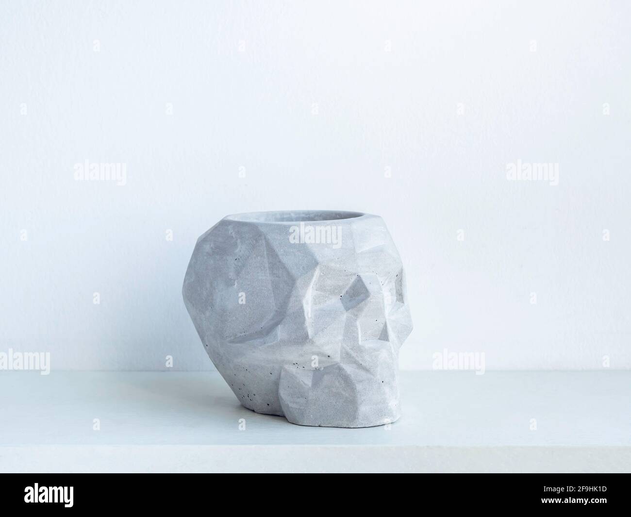 Empty skull shape concrete plant pot on white wooden shelf isolated on ...