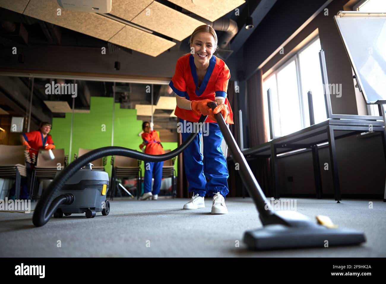 Joyous janitor cleaning the floor in the conference room Stock Photo ...