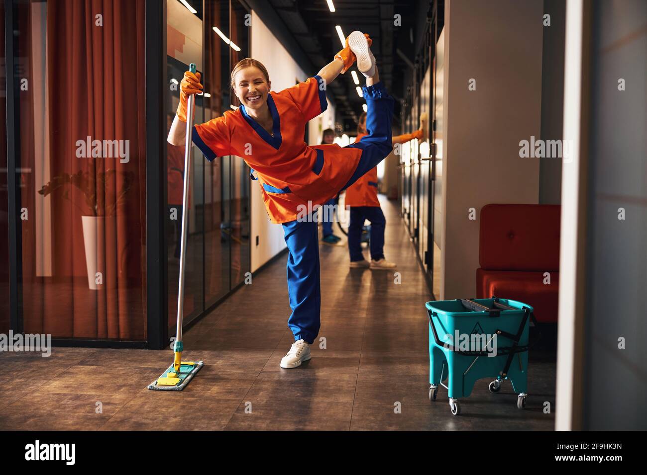Merry worker doing a single-leg stance propped on the mop Stock Photo ... Merry worker doing a single-leg stance propped on the mop Stock Photo ...