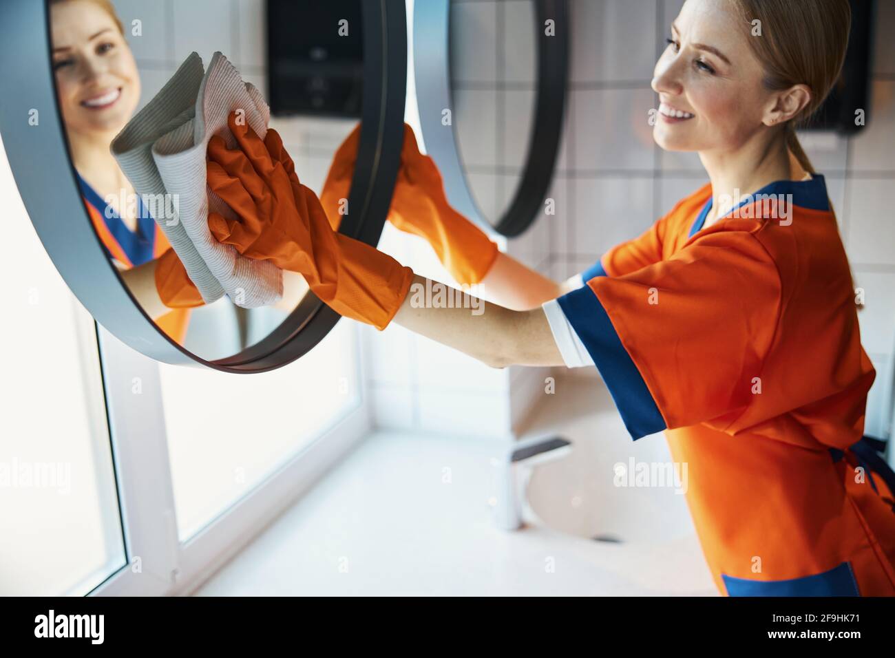 Joyous young janitor cleaning the office bathroom Stock Photo - Alamy