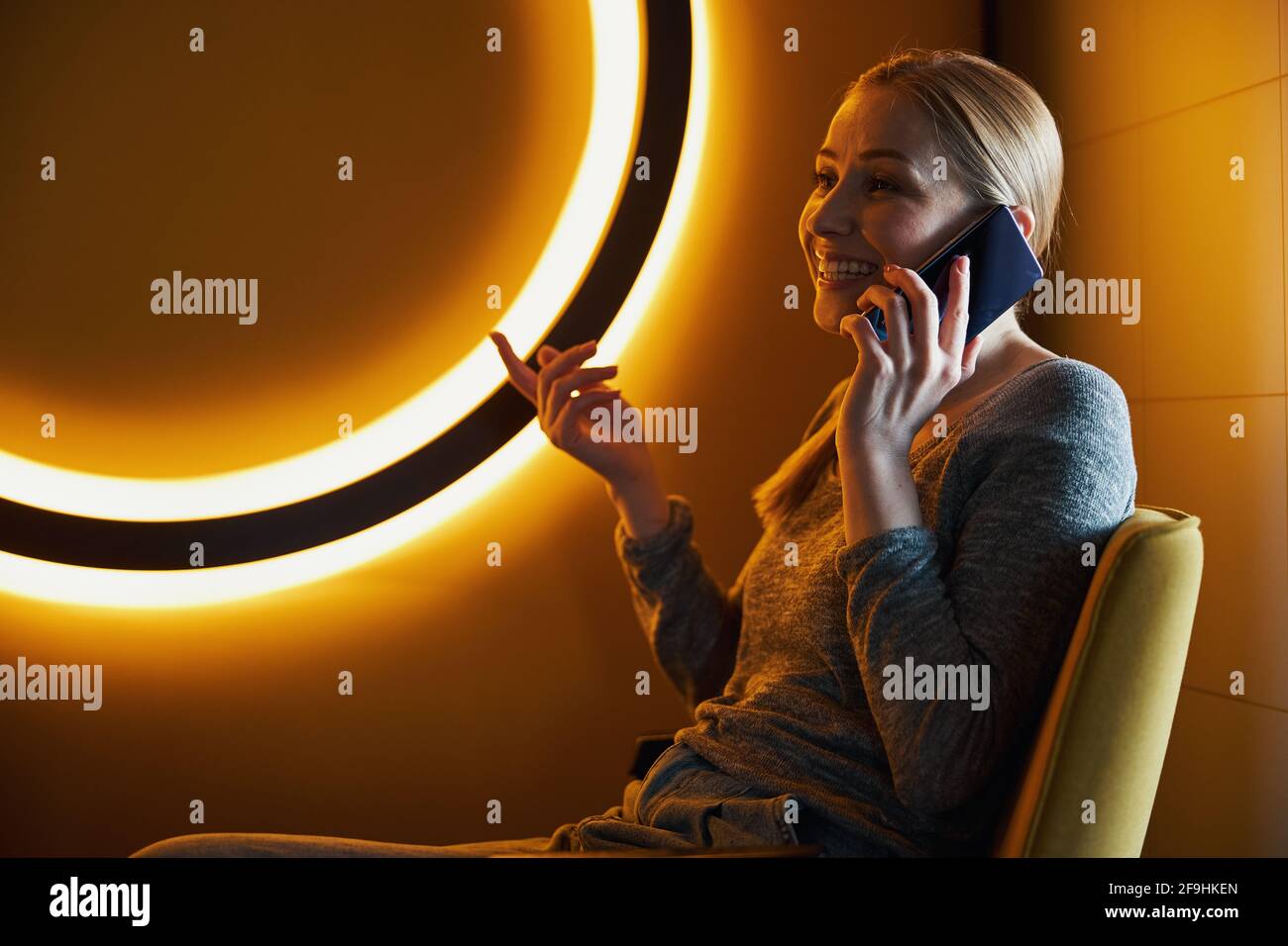 Merry lady seated in the armchair talking on the smartphone Stock Photo ...