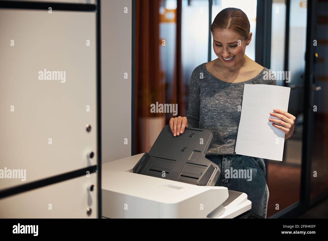 Secretary with a stack of papers standing by the printer Stock Photo ...