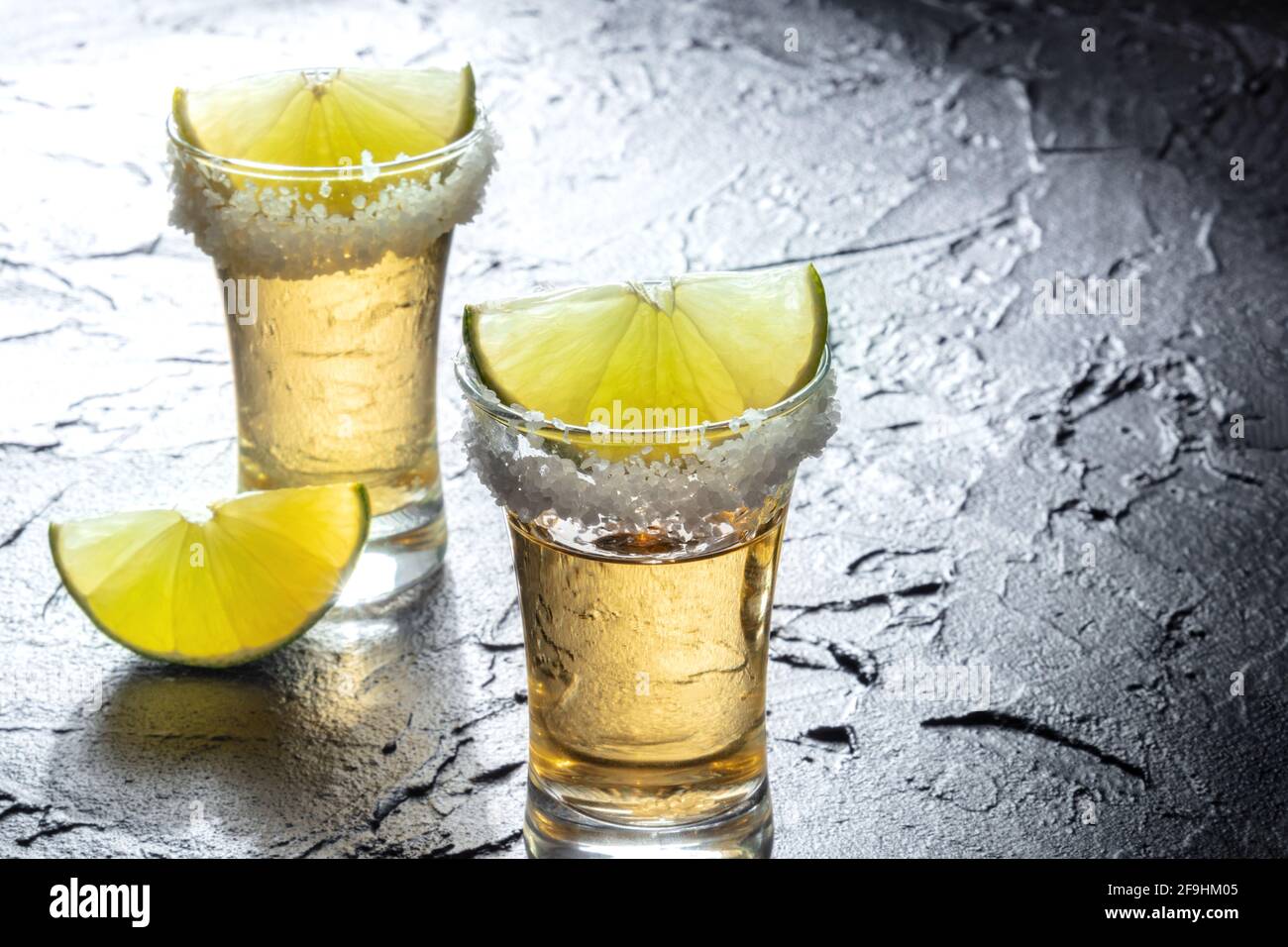 Tequila shots with lime slices on a black background Stock Photo - Alamy