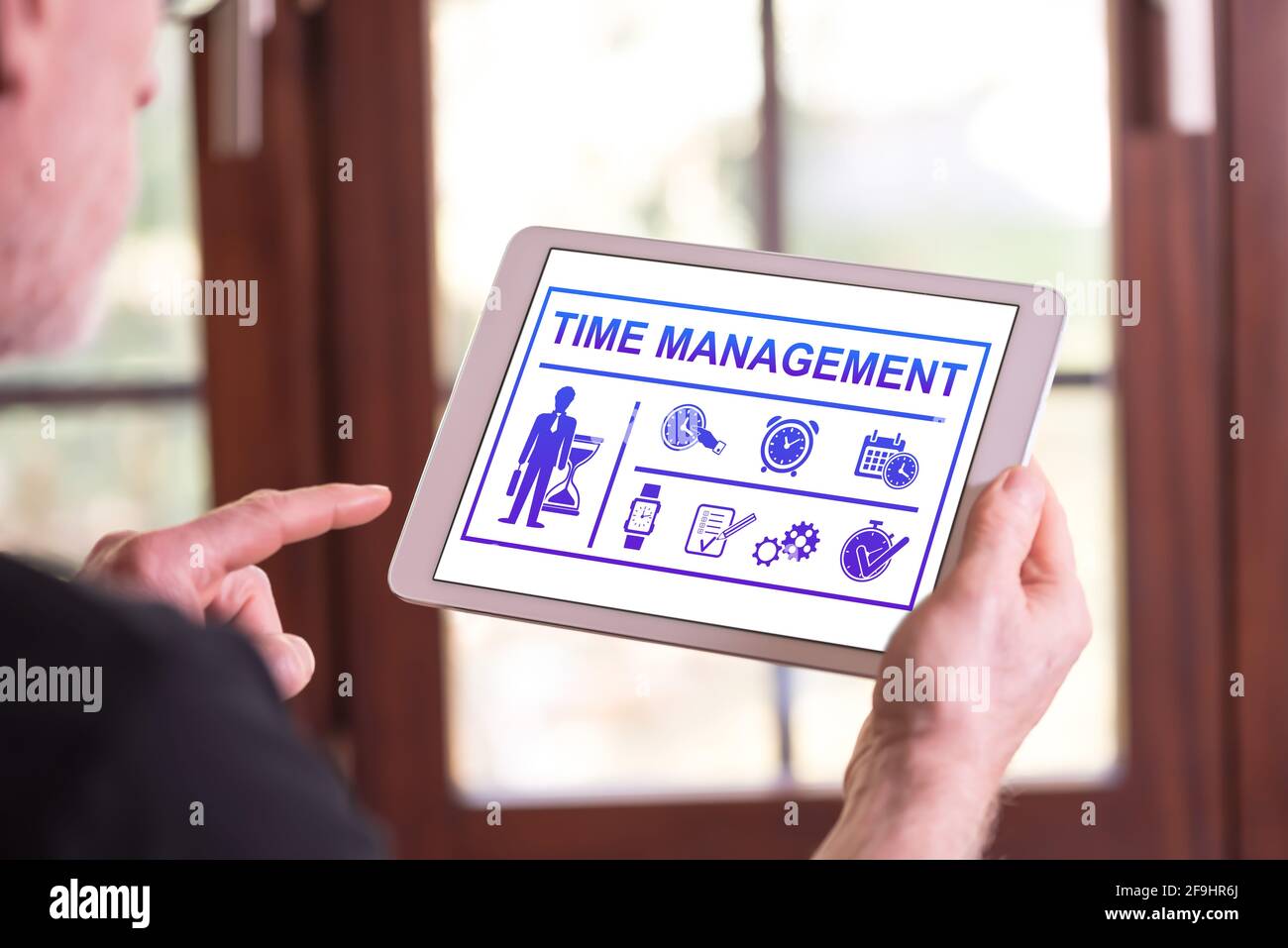 Man holding a tablet showing time management concept Stock Photo - Alamy
