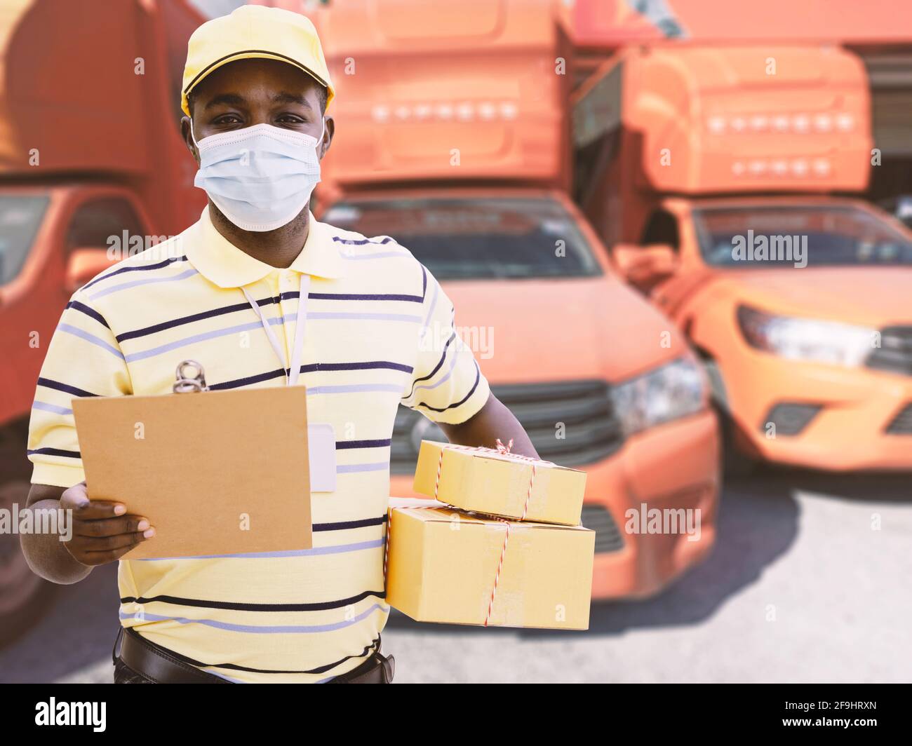 African delivery man holding boxs and cardboard with wearing face mask ...