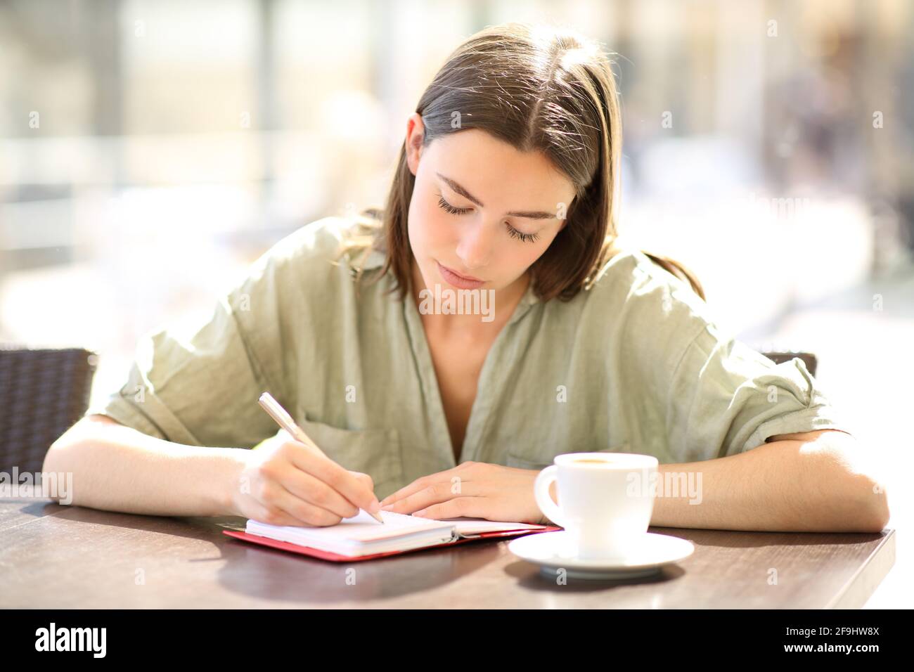 Front view portrait of a serious woman writing on agenda in a coffee ...