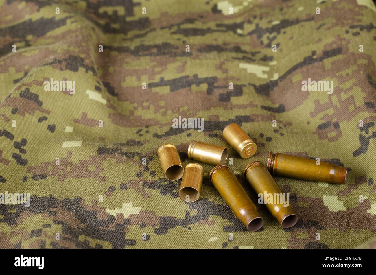 A few random casings on camouflage cloth. A group of pistol and rifle ...