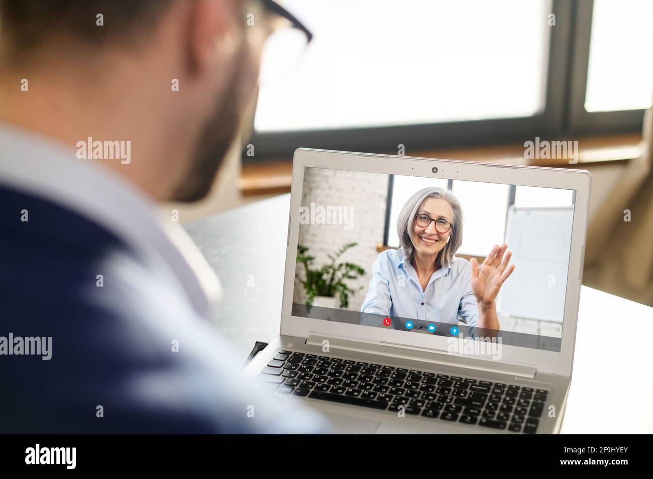 Over the shoulder photo of man sitting in front of a laptop, looking at ...